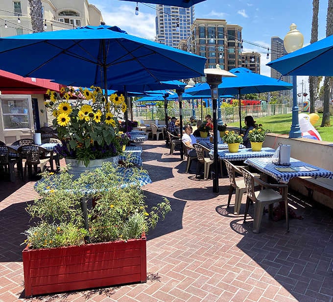 Waterfront patio dining under blue umbrellas, where barbecue tastes even better with harbor views included.