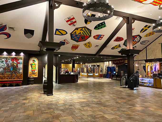 The grand lobby features heraldic shields overhead and gift shops below, medieval commerce meets modern souvenir hunting perfectly.