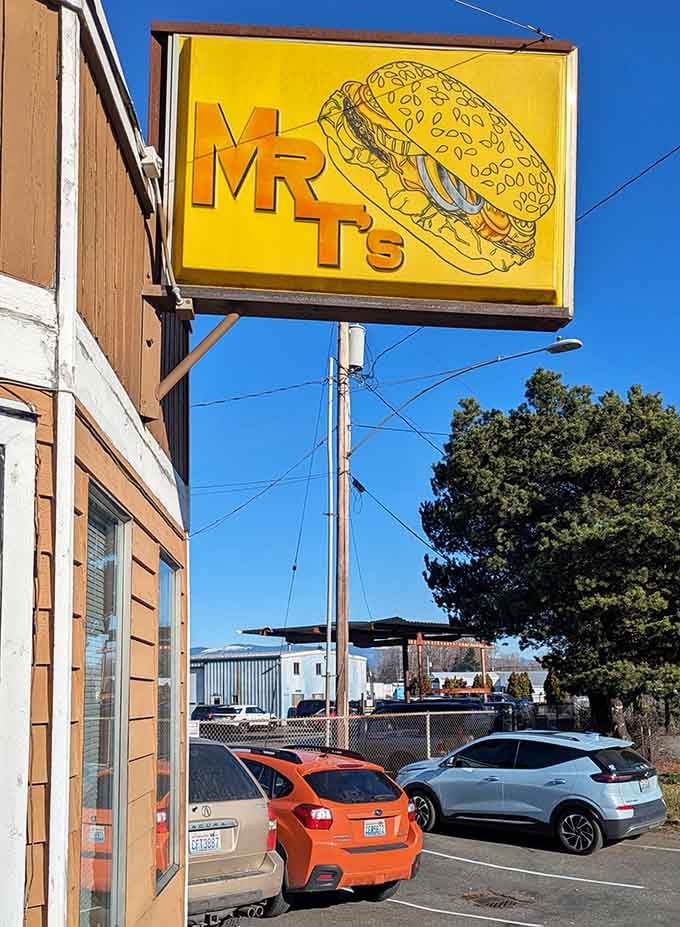 That cheerful yellow sign with the burger graphic beckons hungry travelers off the highway toward breakfast salvation.