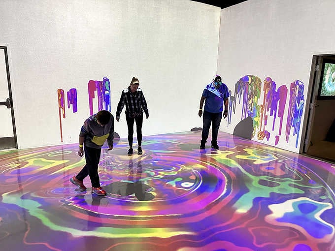 Visitors explore swirling floor projections that respond to movement, turning simple walking into interactive art.
