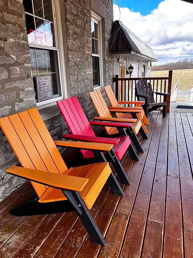 Colorful Adirondack chairs line the porch, inviting you to test the outdoor furniture before committing.