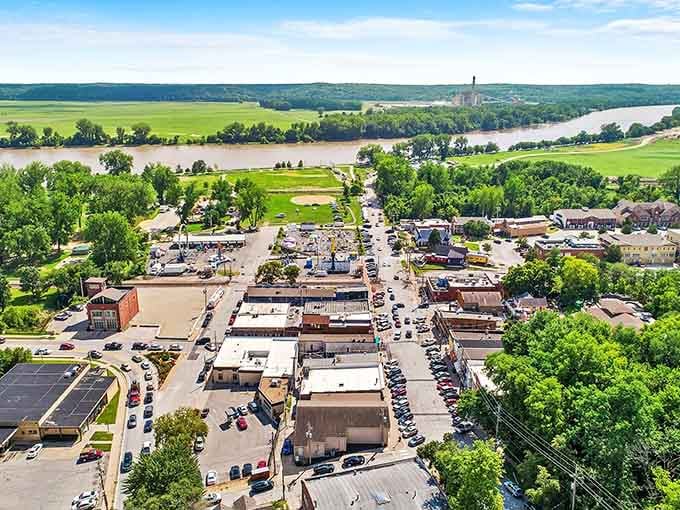 From above, the town's tiered magic reveals itself completely, buildings and trees cascading toward that ancient muddy river.