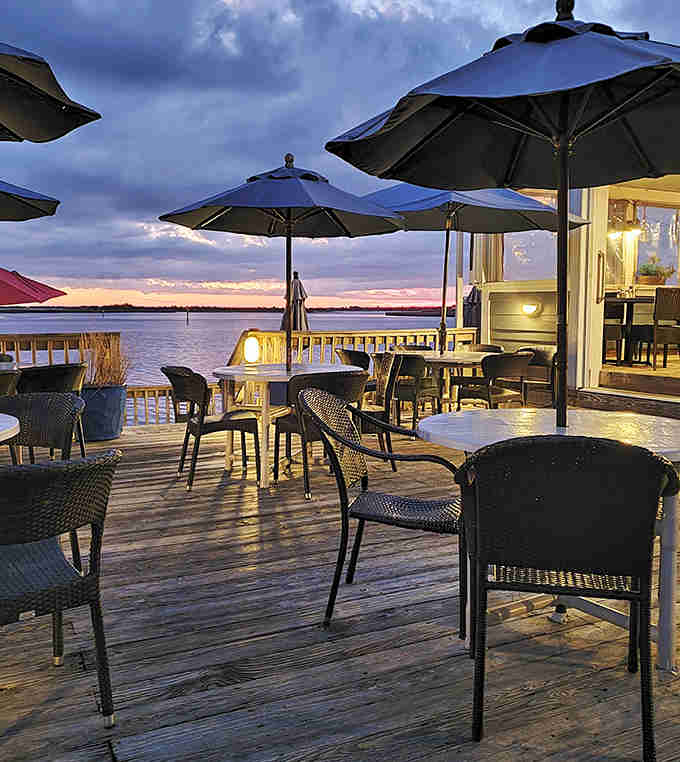 Outdoor deck seating with umbrellas and sunset views, because sometimes dinner tastes better with a waterfront breeze involved.