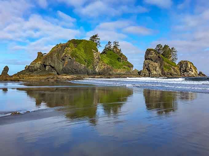 Sea stacks mirror perfectly in wet sand, doubling the drama and giving your camera something to brag about.