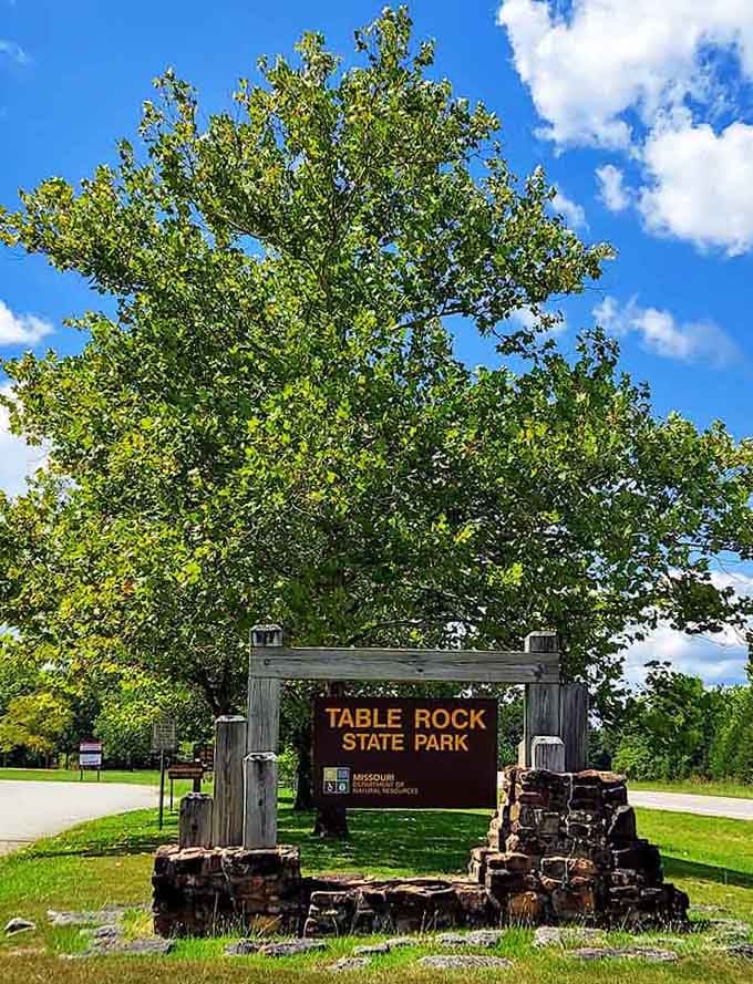 The rustic entrance sign welcomes visitors with stone pillars and carved wood, promising adventures beyond that green canopy.