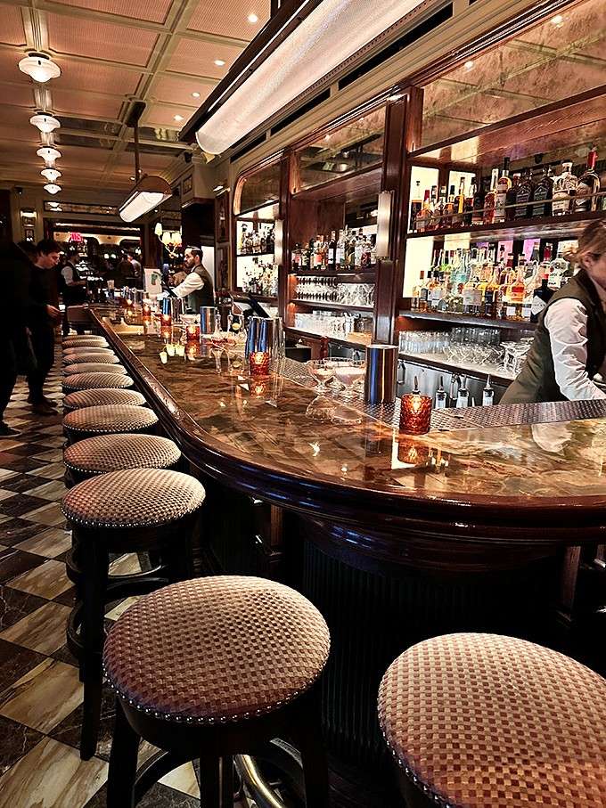 The bar gleams with polished wood and promise, lined with seats that offer front-row views to the cocktail magic happening.