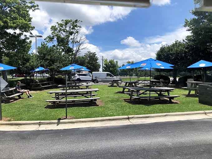 Outdoor picnic tables under blue umbrellas offer the perfect spot to enjoy award-winning barbecue in the fresh air.