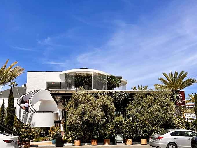 The distinctive curved architecture and lush landscaping signal that something extraordinary is happening inside this coastal pizza haven.