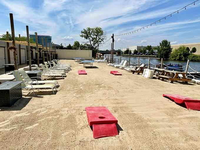 Cornhole boards on sand by the river create the ultimate "did I really drive here" moment of confusion.