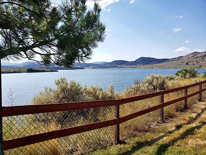 That red fence frames the lake perfectly, like nature hung its own artwork just for your Instagram feed.