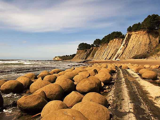 Nature's bowling alley stretches along the shore, where perfectly round boulders line up like they're waiting for a strike.