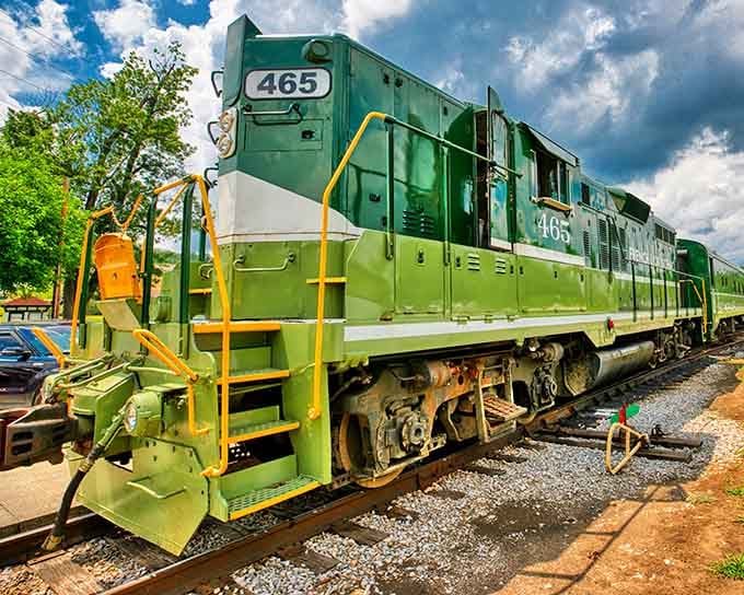 That green locomotive gleams like an emerald against dramatic clouds, ready to transport you back to simpler times.