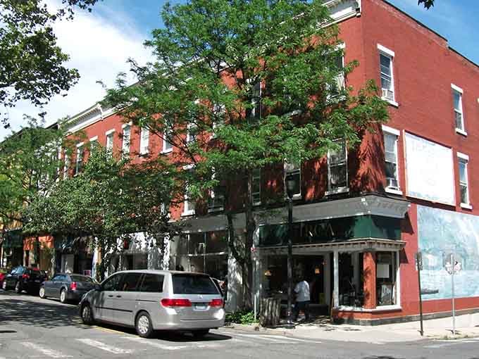 Classic brick storefronts shaded by leafy trees create the perfect backdrop for a leisurely afternoon stroll.