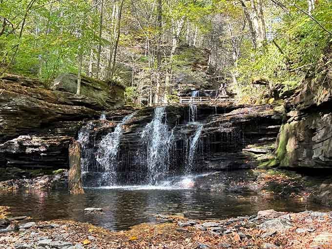 Nature's own curtain call: multiple waterfalls cascade over layered rock like a liquid staircase into crystal pools below.