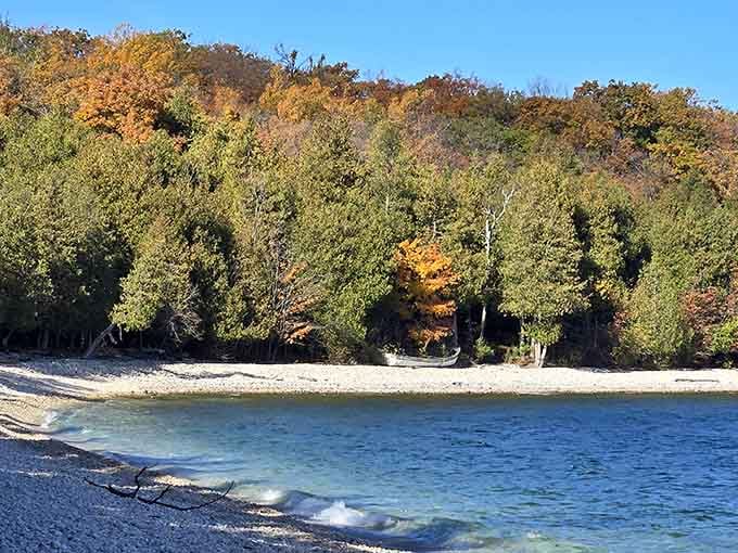 Autumn's golden palette meets crystal-clear waters where smooth limestone pebbles create one of Earth's rarest beaches.