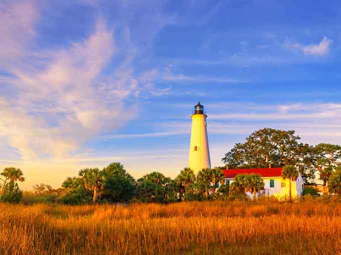Golden hour transforms this cheerful yellow tower into a glowing beacon surrounded by marsh grass like nature's own painting.
