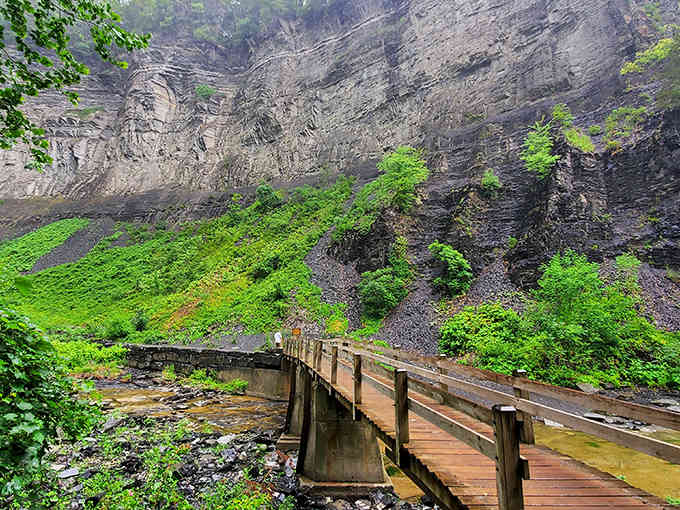 That wooden bridge leads straight into a gorge where towering rock walls make you feel wonderfully small.