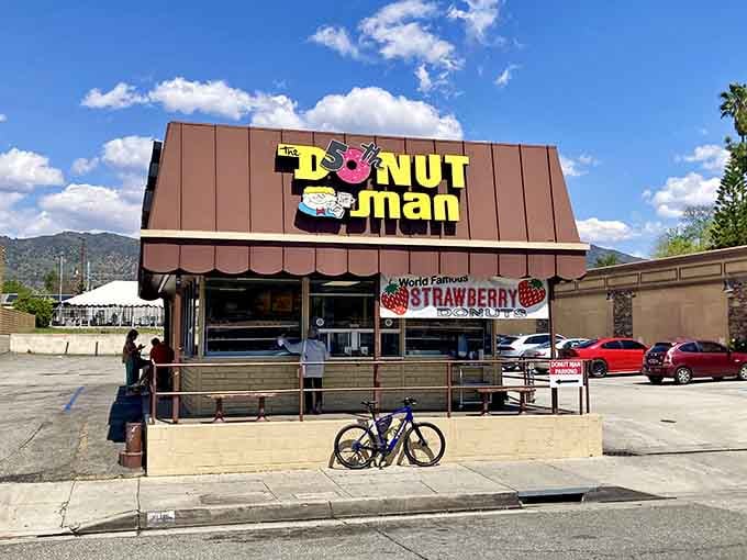 That cheerful sign against blue skies promises fresh strawberry donuts that'll make your taste buds sing with joy.