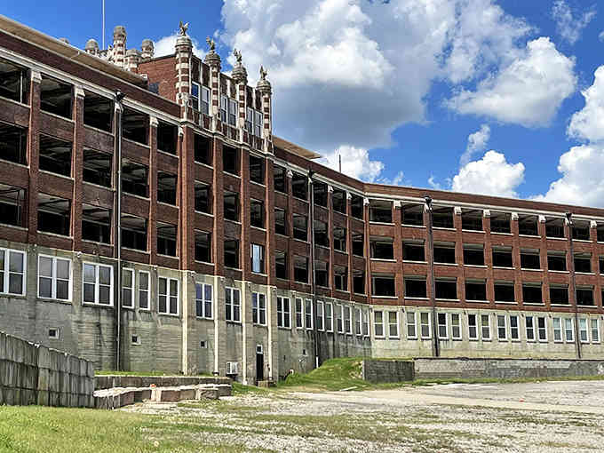 This imposing brick fortress stands like a Gothic castle against Kentucky's blue sky, its ornate towers watching over empty grounds.