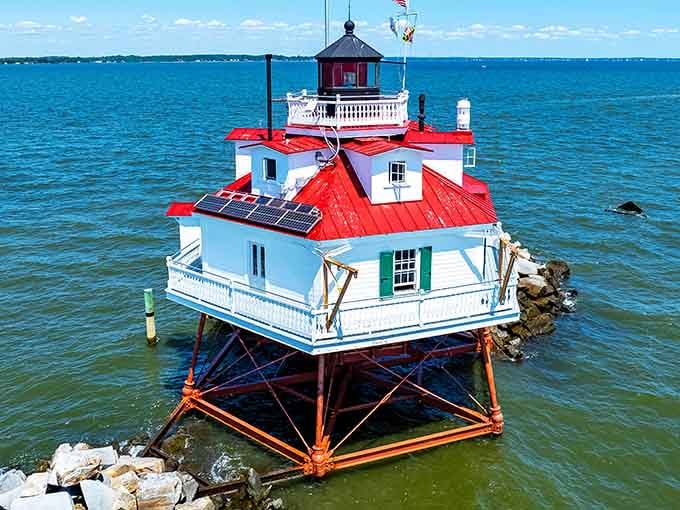 That bright red roof against the blue bay makes this screwpile lighthouse look like a floating birthday cake.