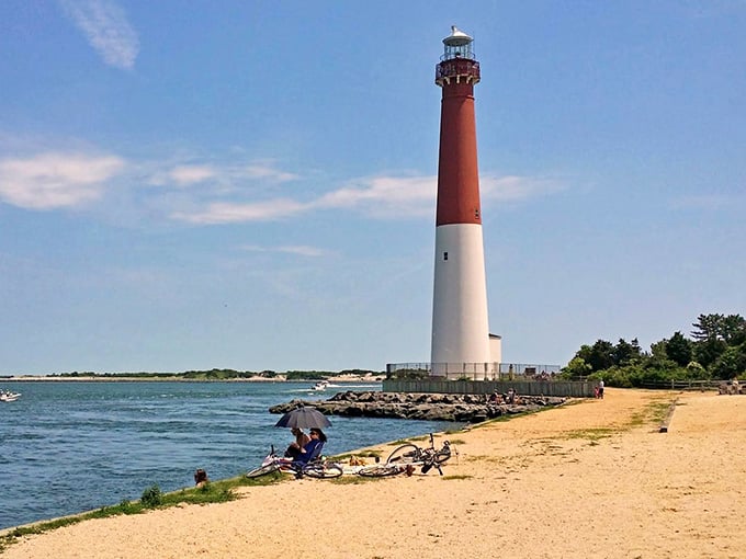 Families spread out on the sandy beach while this iconic sentinel watches over boats gliding across sparkling water.