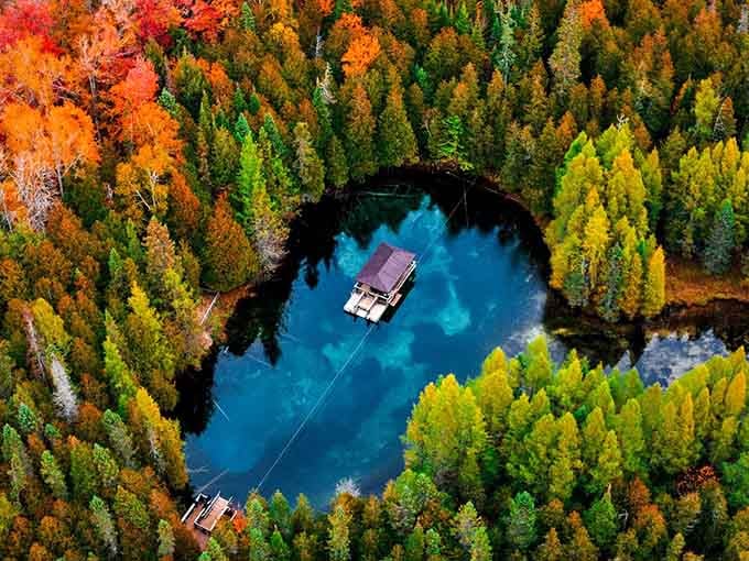 Fall colors frame this turquoise gem like nature's own picture frame, proving Michigan does autumn better than anyone.