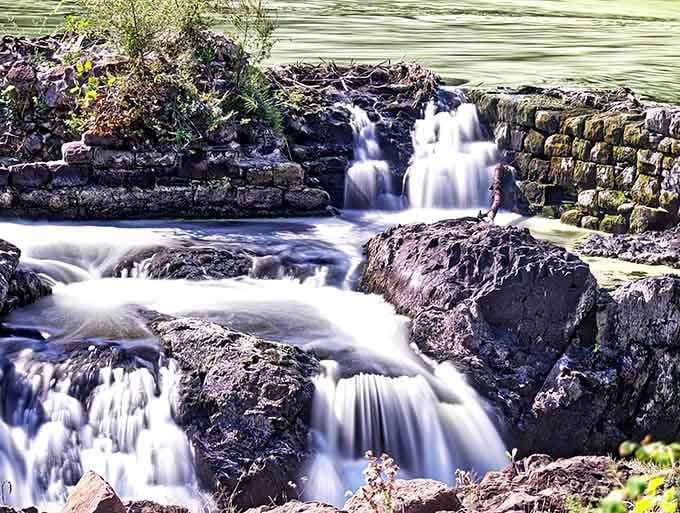 Multiple cascades tumble over ancient rock ledges like liquid silk, creating a mesmerizing staircase of rushing water.