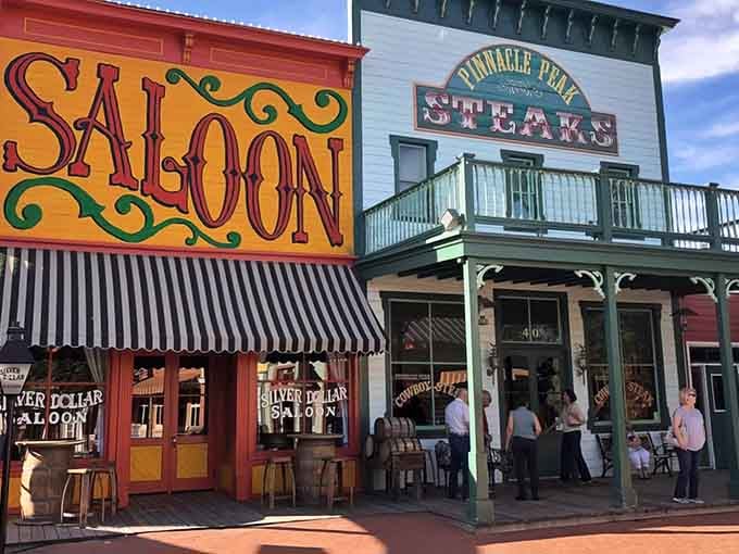 The saloon's ornate lettering and green-trimmed balcony create an authentic frontier town atmosphere under blue skies.