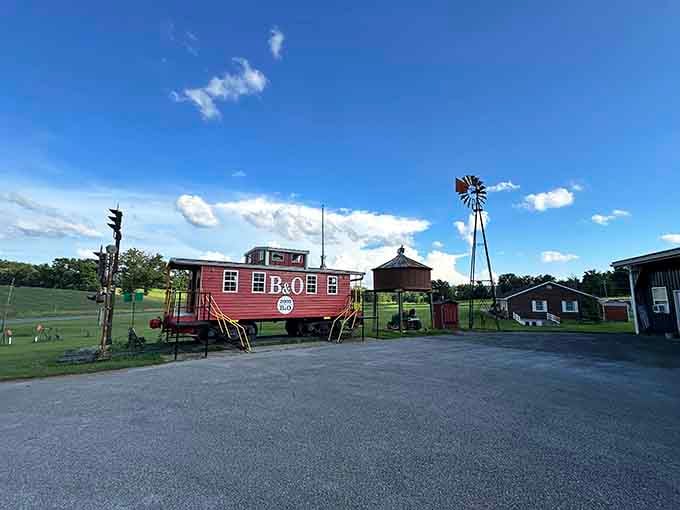 That red caboose under blue skies proves someone's collecting dreams, not just old trains and windmills.