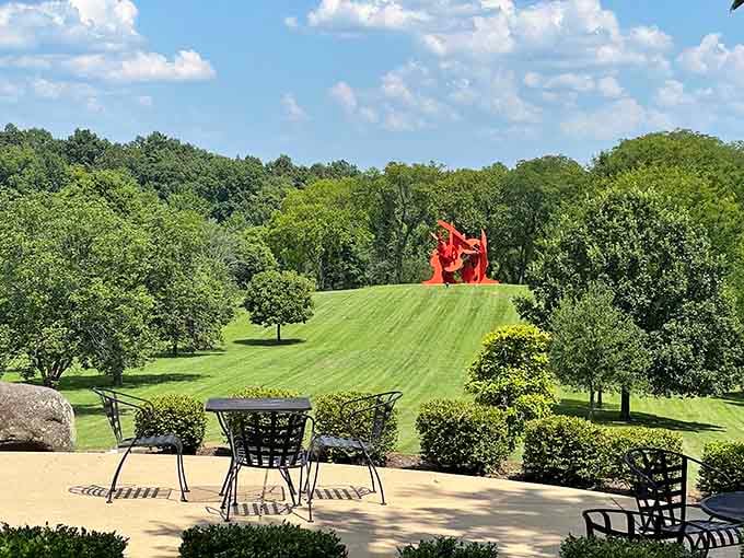 Picture perfect patio dining with a red sculpture standing sentinel on the manicured lawn beyond.