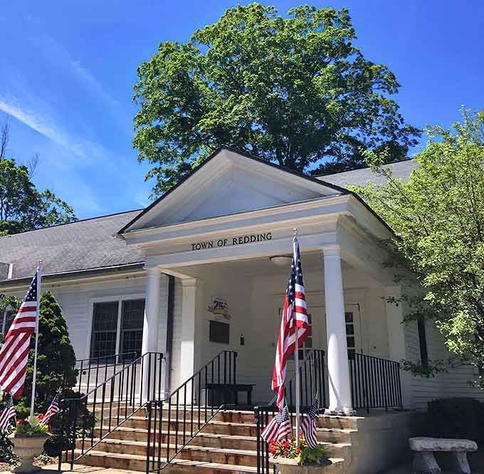 Classic white columns and American flags frame this town hall like a postcard from simpler times.