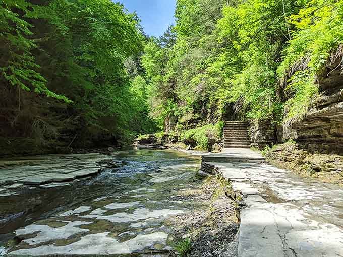 The pathway hugs the stream through towering rock walls, where sunlight filters down like nature's own spotlight show.