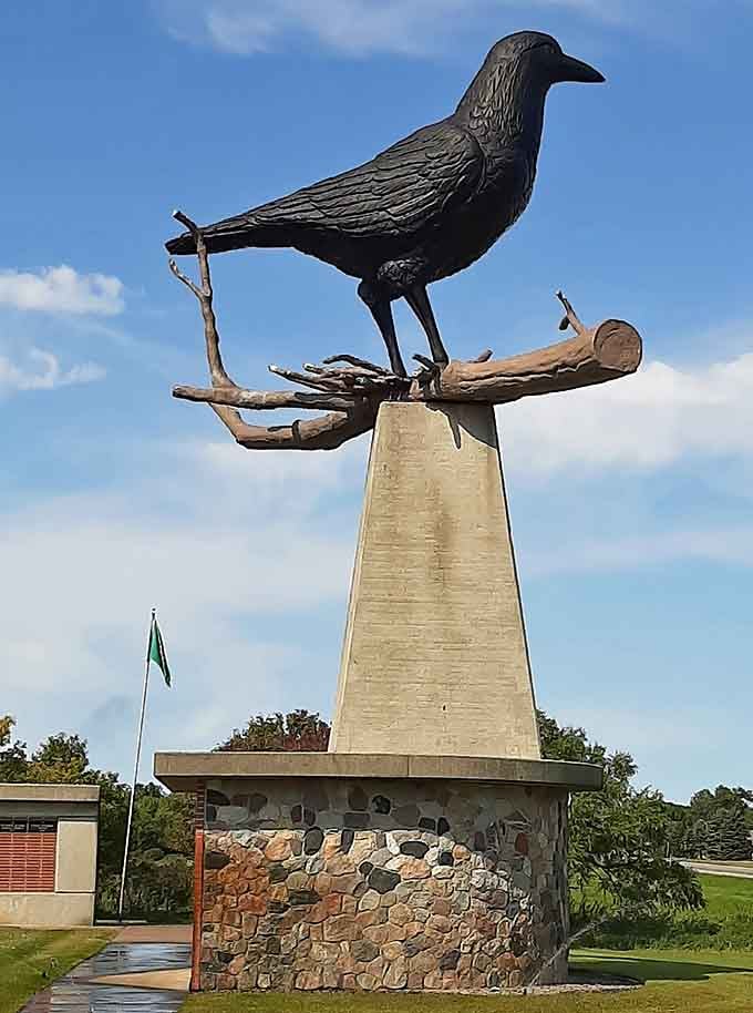 Against wispy clouds, this metallic crow surveys its domain like a feathered king watching over loyal subjects.
