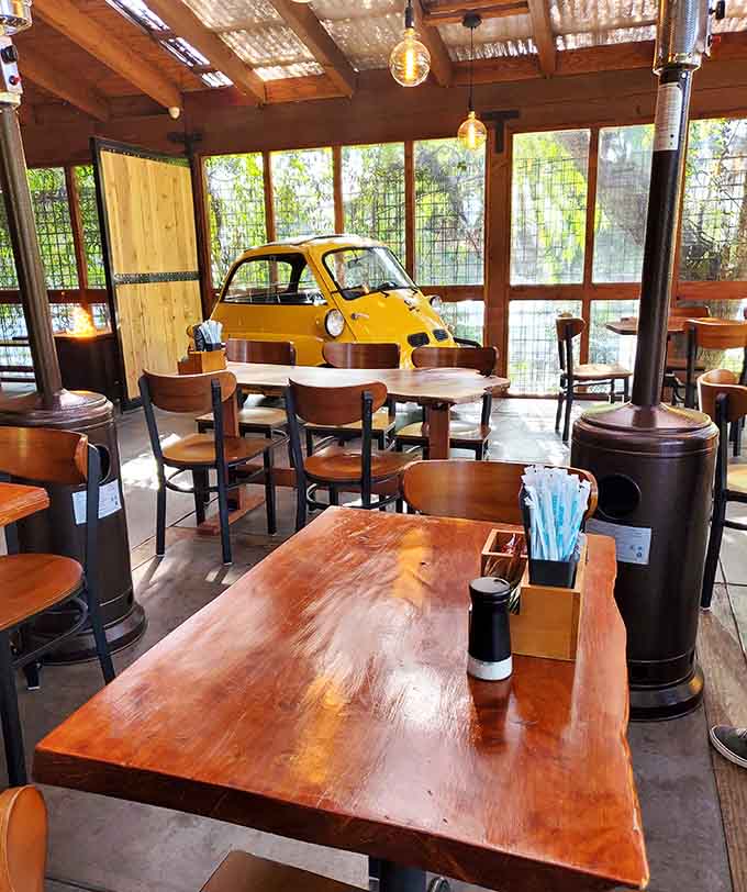 A vintage yellow car parked inside the dining room proves someone here understands that breakfast should always include a conversation starter.