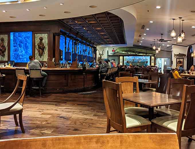 Rich wood tones meet ethereal blue light, creating an atmosphere that's equal parts sophisticated steakhouse and marine wonderland.