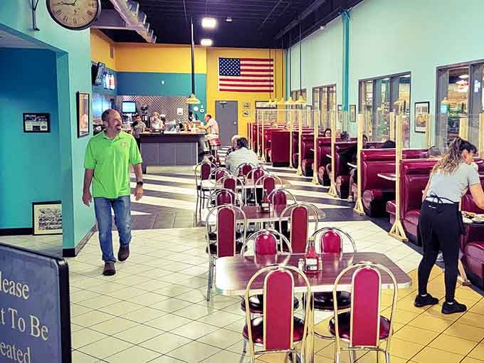 Bright turquoise walls and cherry-red booths create a retro diner vibe that somehow makes tractors and toast feel perfectly natural.