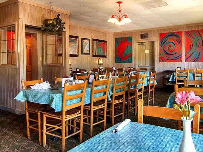 Wood paneling, colorful art, and turquoise tablecloths create a dining room that feels like your favorite beach house.