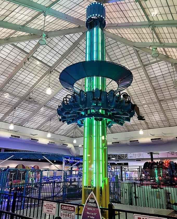 The Drop Tower glows like a beacon of questionable life choices you'll absolutely make anyway.