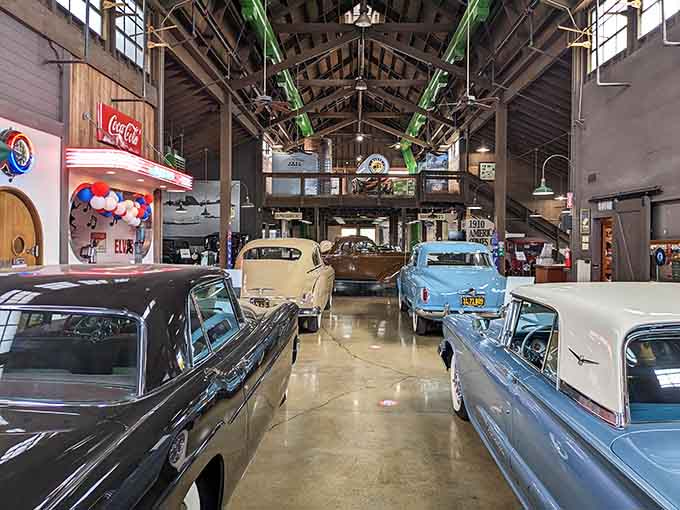 Cathedral ceilings meet classic cars in this soaring space where vintage Coca-Cola signs share billing with gleaming automotive legends.