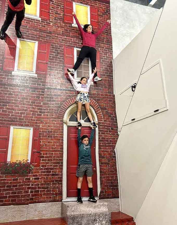 Suddenly everyone's a circus performer, stacking themselves like human Jenga pieces against a perfectly normal brick wall. Sure.