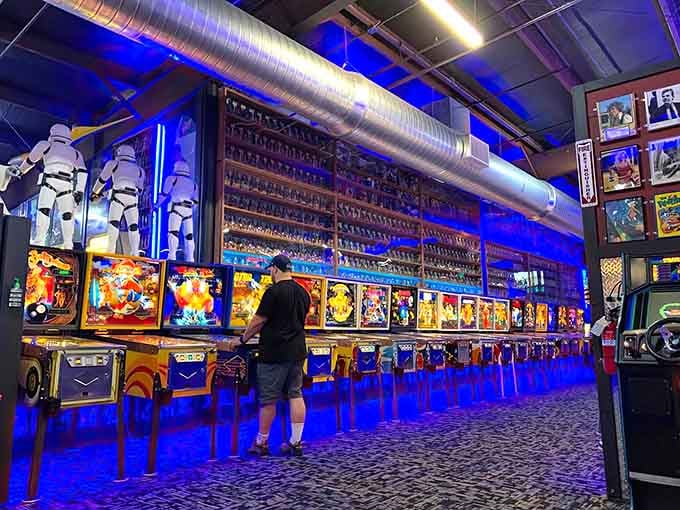 Life-size Stormtroopers stand guard over an impressive lineup of pinball tables bathed in that perfect blue glow.