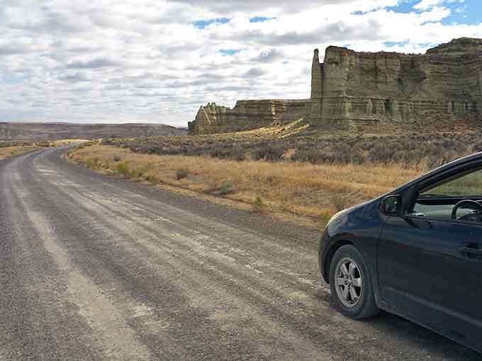 The gravel road winds past geological wonders that make you question whether your GPS accidentally routed you through Mars.