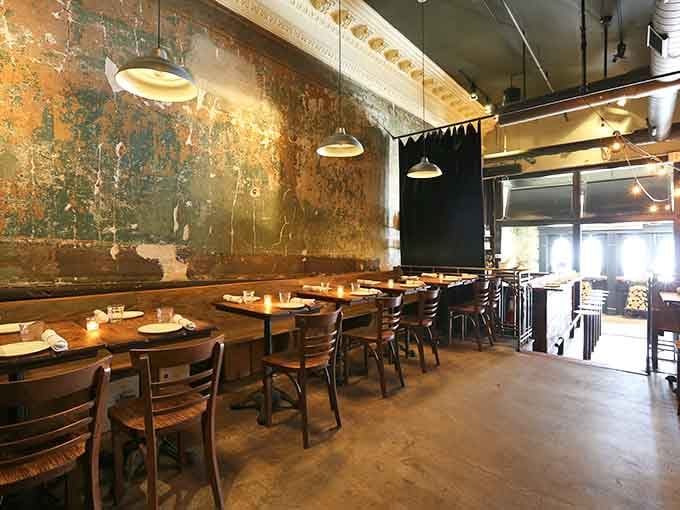 Weathered walls tell stories while pendant lights illuminate the real narrative: exceptional pizza happening right before your eyes.