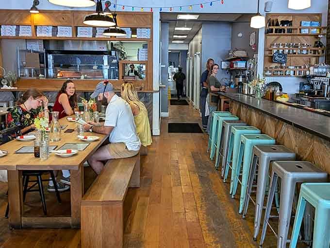 Light wood, mint stools, and an open kitchen create the kind of welcoming vibe that makes strangers become friends over pizza.
