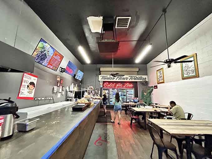 Step inside where ceiling fans spin lazily above wooden tables, and the real magic happens behind that counter.