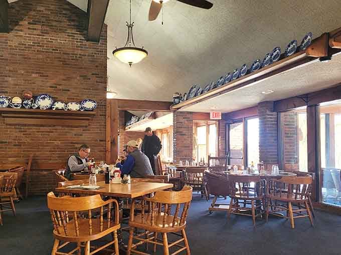 Exposed brick, wooden chairs, and decorative plates lining the walls create timeless steakhouse charm that never goes out of style.