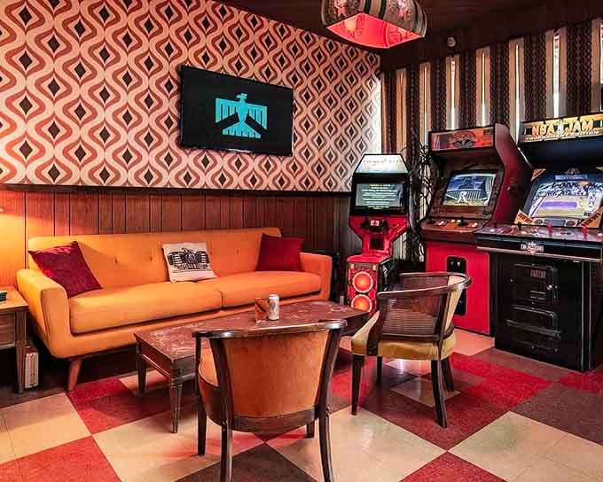 Orange couches and geometric wallpaper create a living room vibe that's equal parts Austin Powers and absolutely perfect.