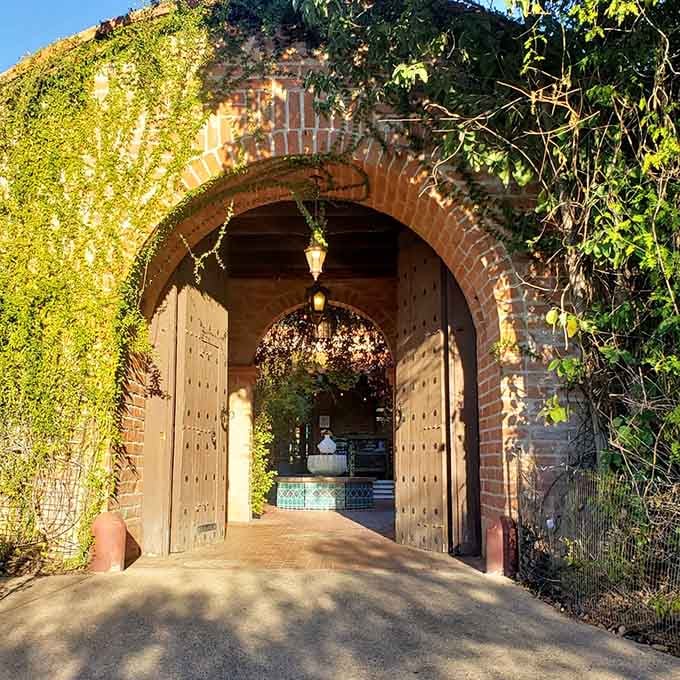 This vine-draped brick archway welcomes visitors into a world where Old World charm meets Sonoran Desert magic.