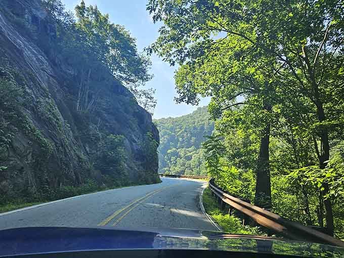 Drive along this winding mountain road where every curve offers stunning views of the lush greenery and rugged rocky cliffs.