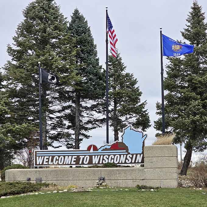 That stone monument with the flags waving proudly is basically Wisconsin giving you an official bear hug at the border.